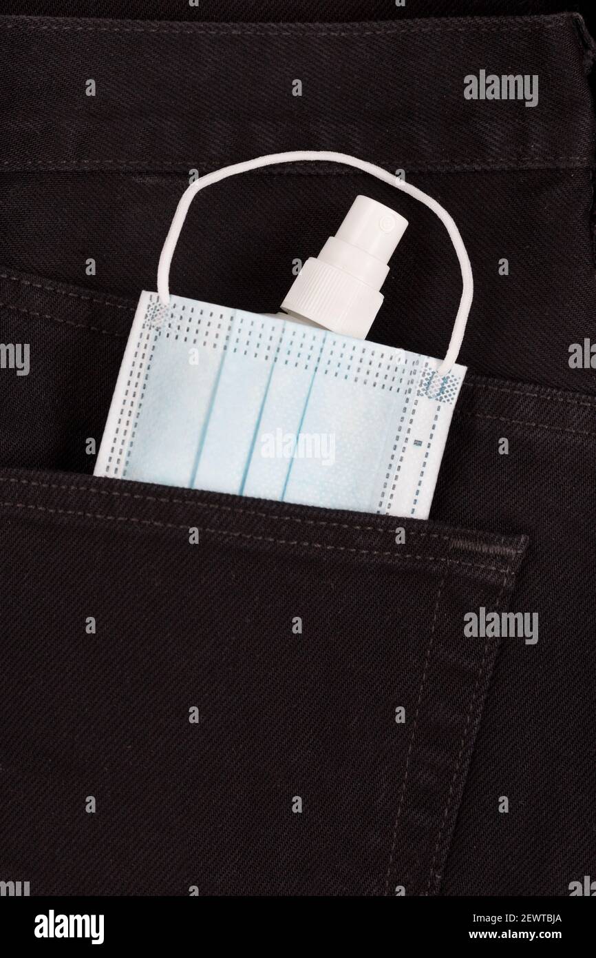 Protective face mask and hand sanitizer spray are lying in back pocket ...
