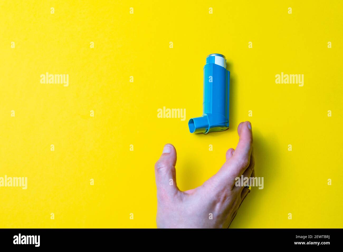 Horizontal photograph of a hand holding an asthma inhaler. Remedy for ...