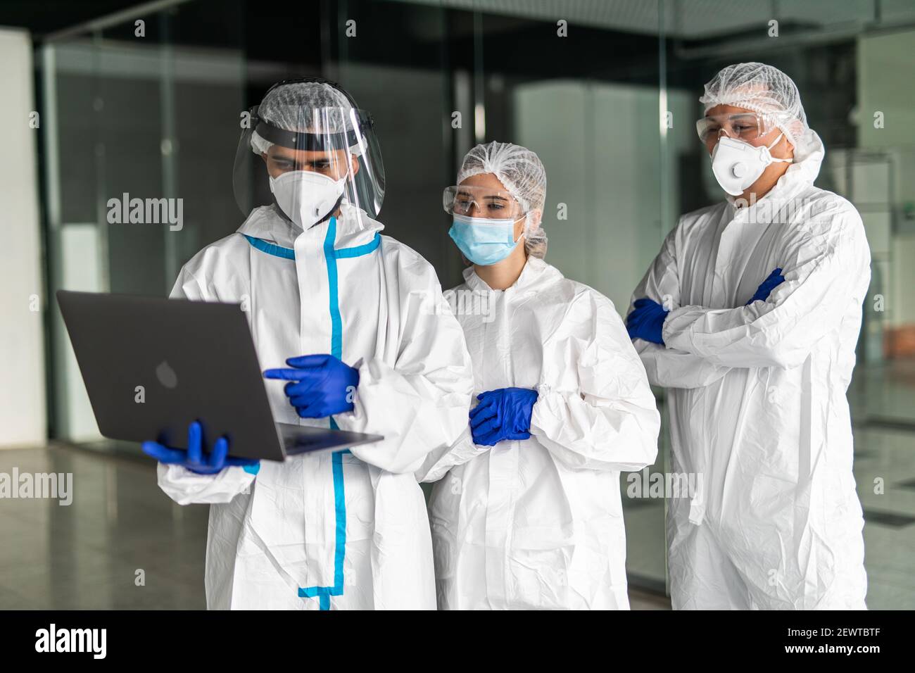Medical workers in hazmat suit looking laptop computer inside clinic ...