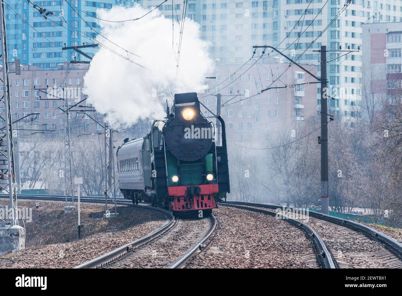 Retro steam train moves on the city background Stock Photo - Alamy