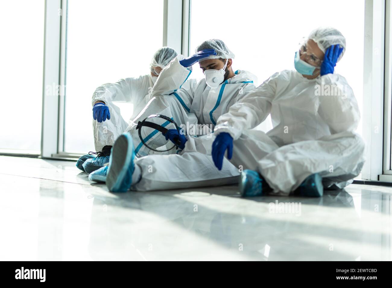 Tired three doctors sit back to back on the floor during a heavy shift ...
