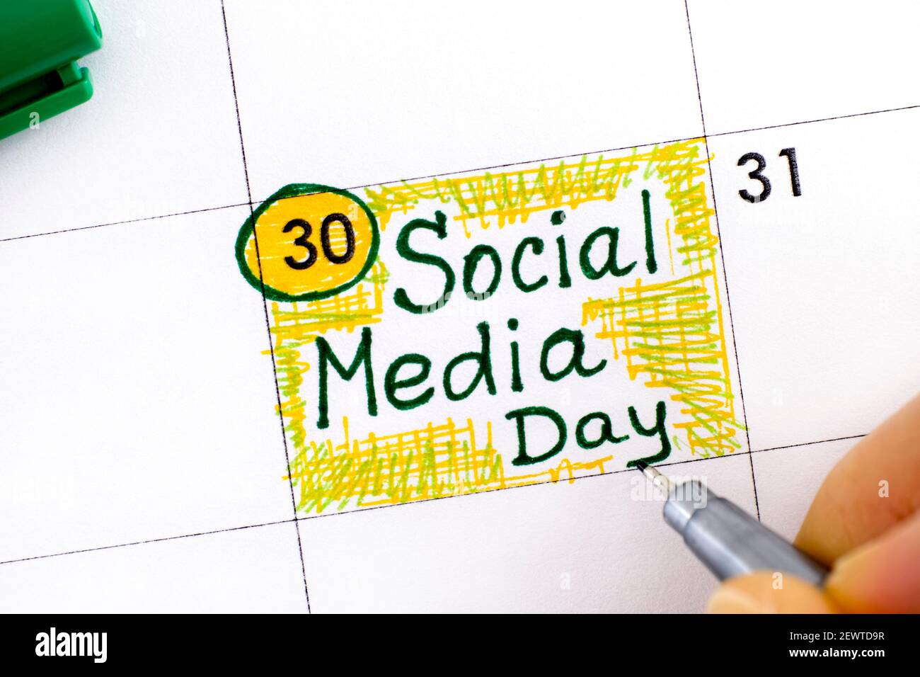 Woman fingers with pen writing reminder Social Media Day in calendar ...