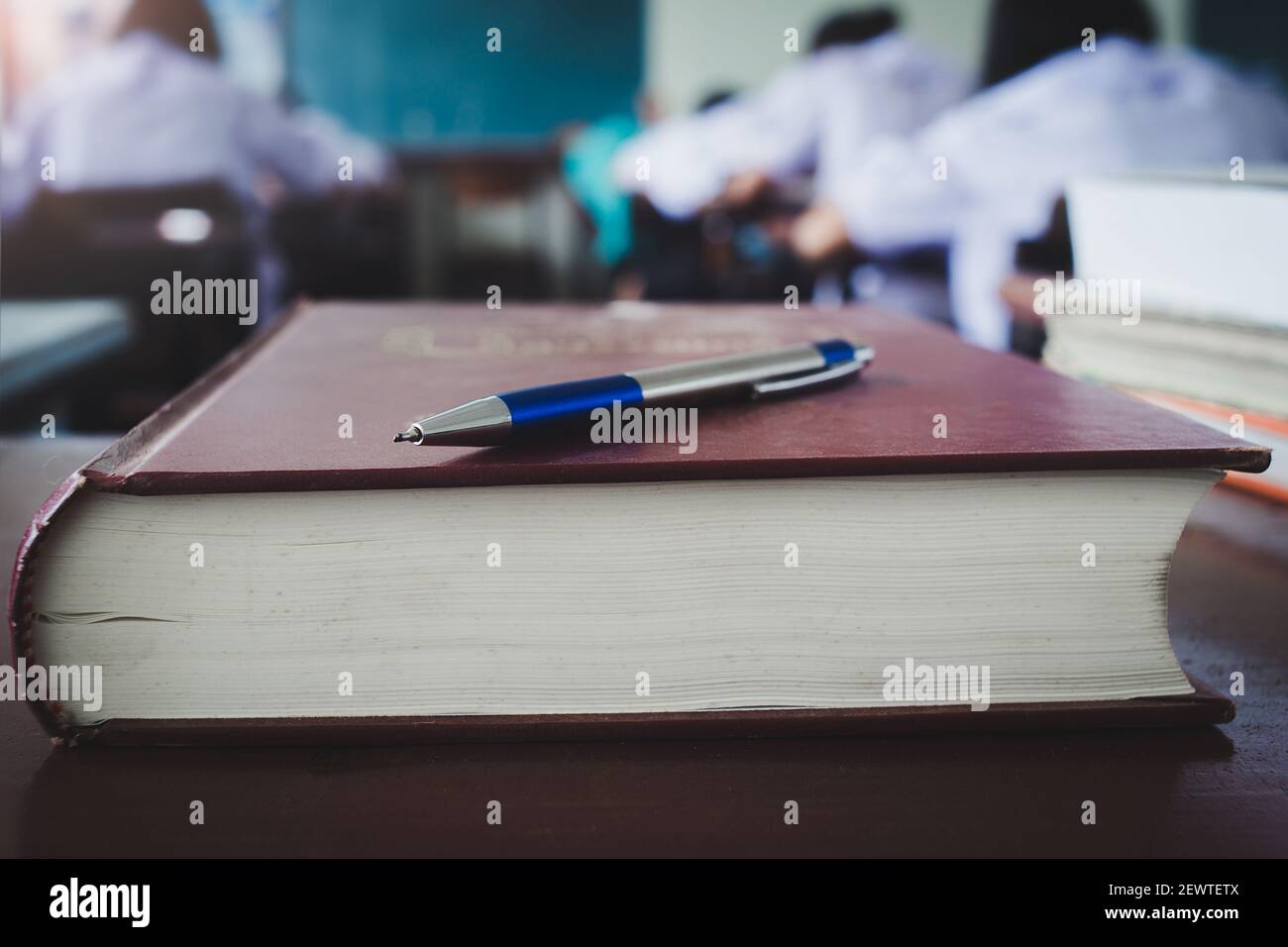 Old book and the pen stand on the desk with students taking exam with ...