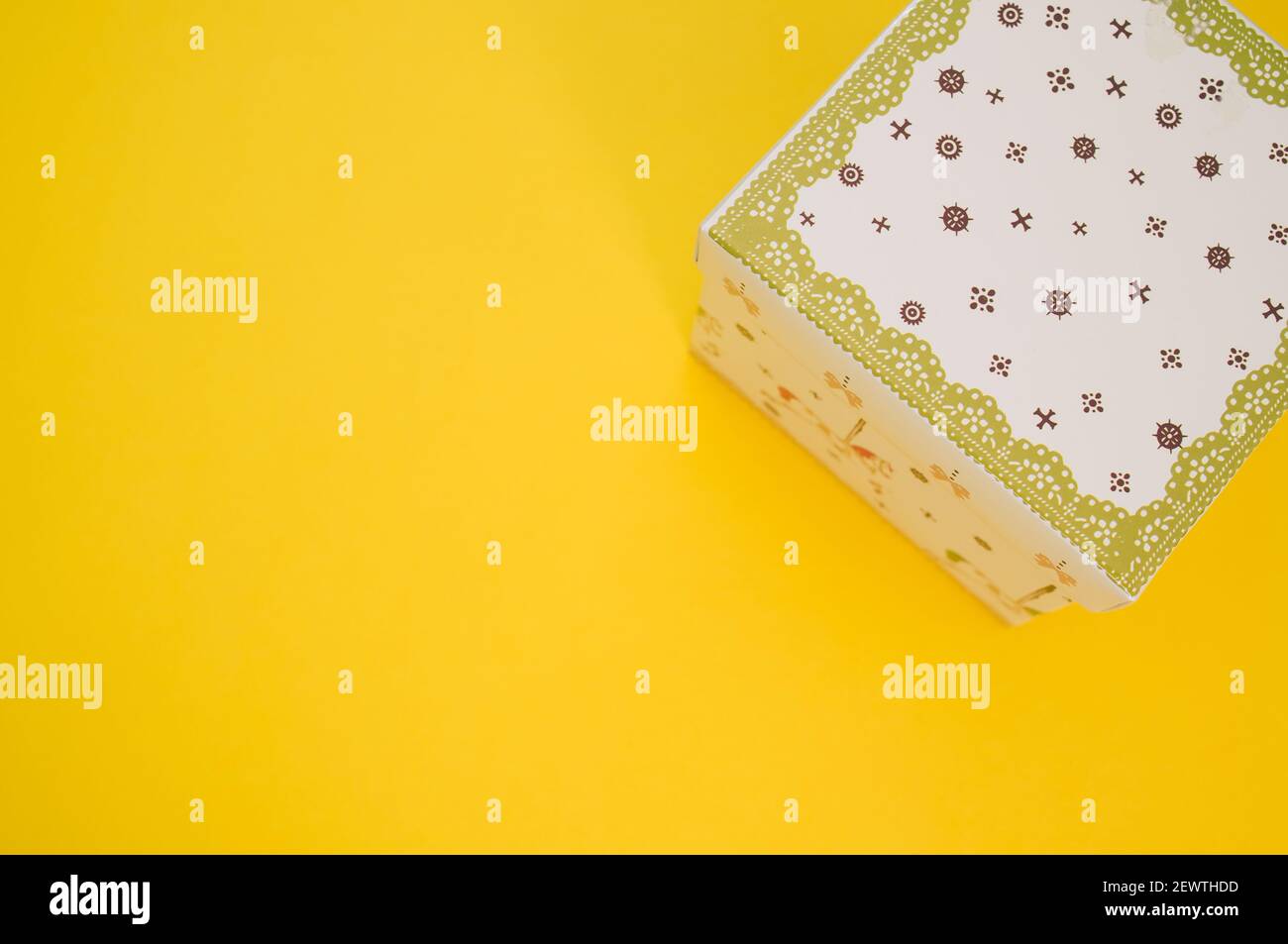 White ornamented paper box in the bright yellow background with copy ...