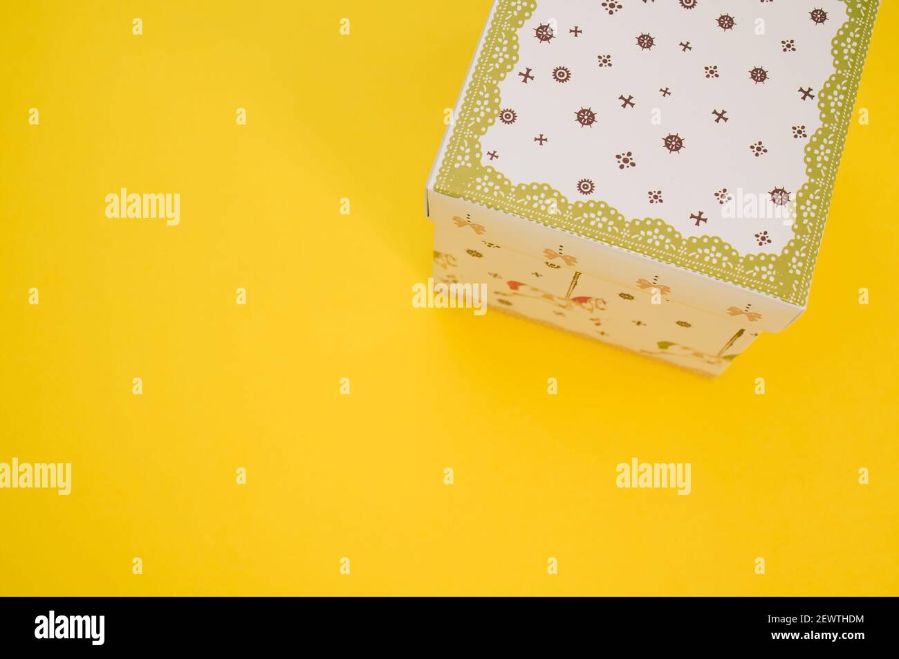 A cube paper box with beautiful ornaments isolated in the bright yellow ...