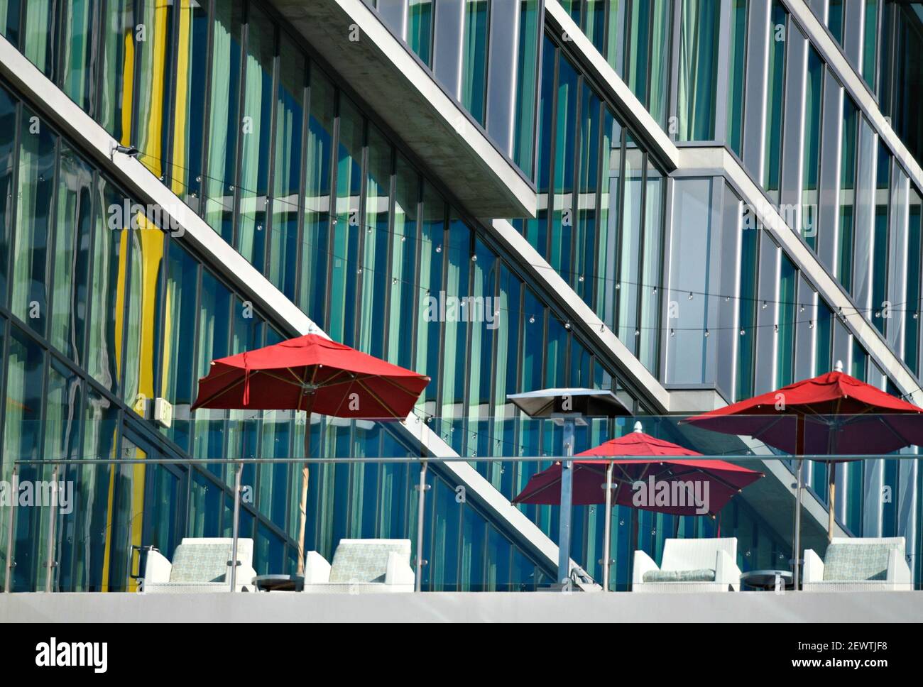 Modern design high-rise building glass facade with three red parasols ...
