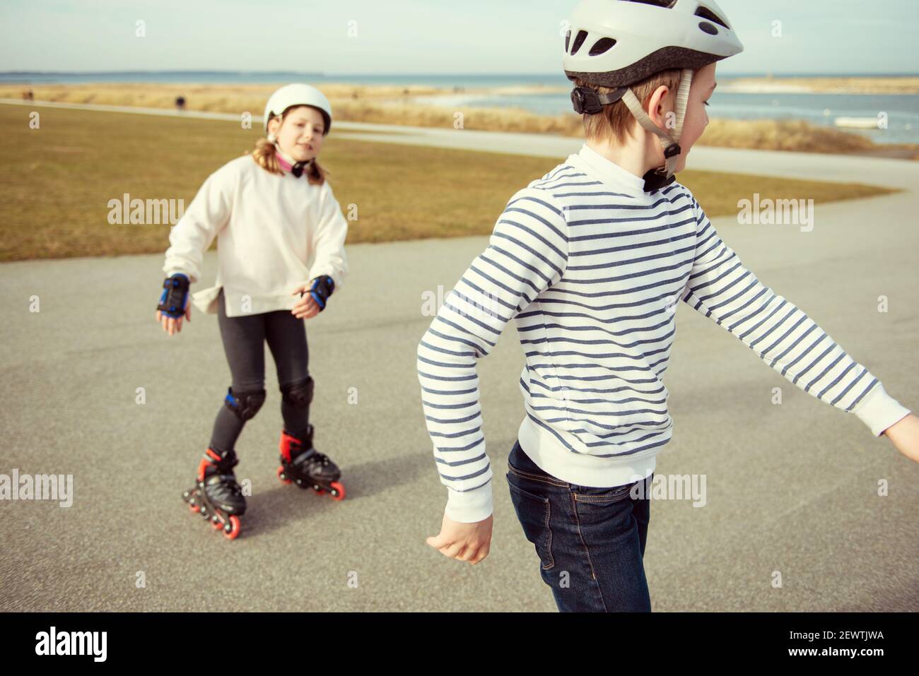 Happy siblings teenager boy and girl having fun during inline skating ...