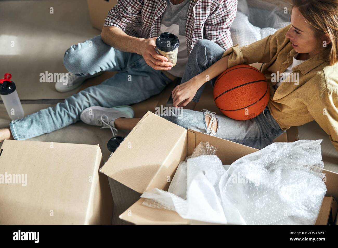 Two young people sitting on the floor among carton boxes Stock Photo ...