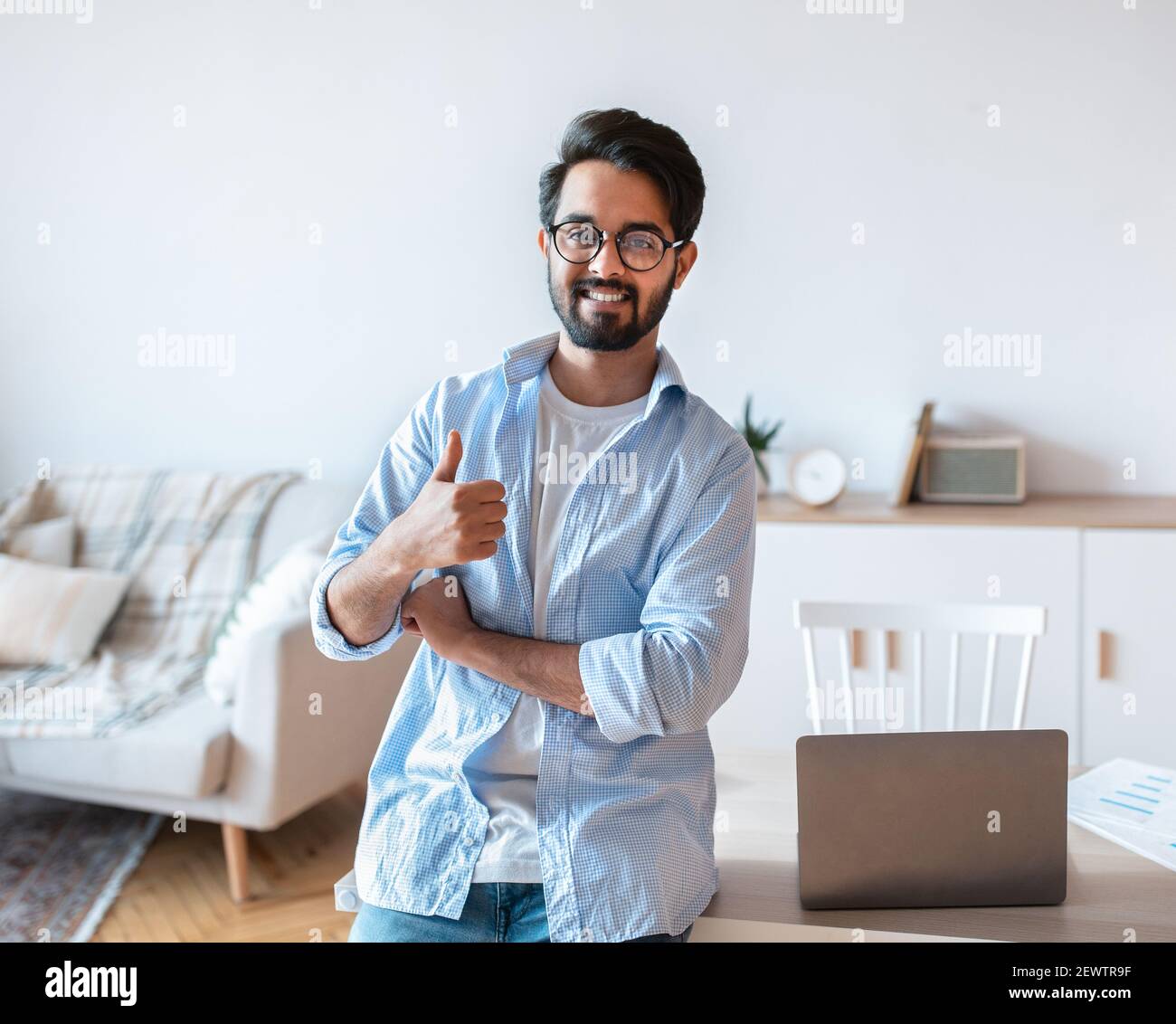 Positive Eastern Freelancer Guy Standing Near Desk With Laptop Showing ...