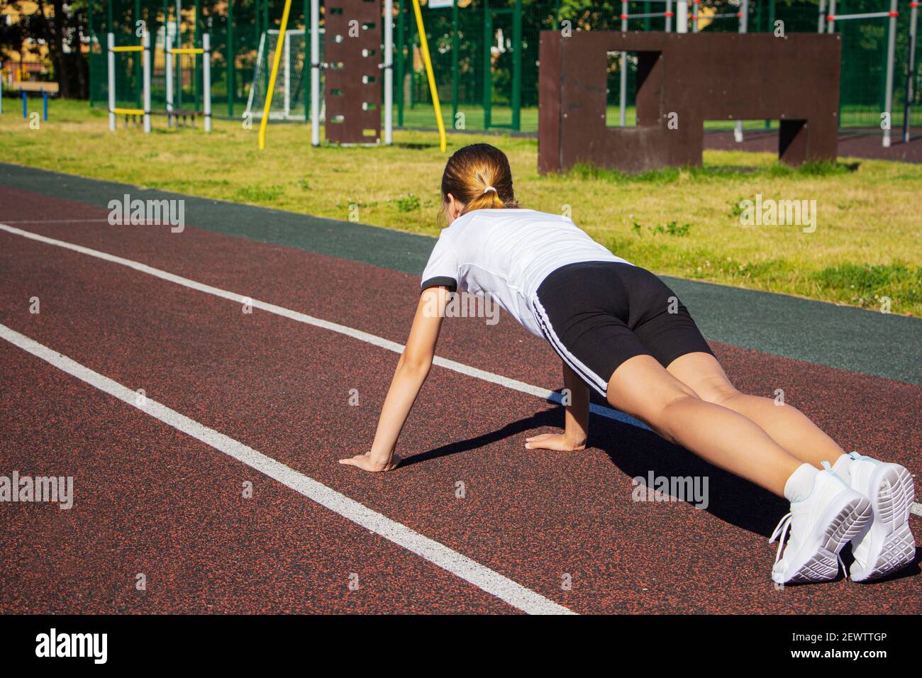a teenage girl does push-UPS on the Playground. Fitness, sports, health ...