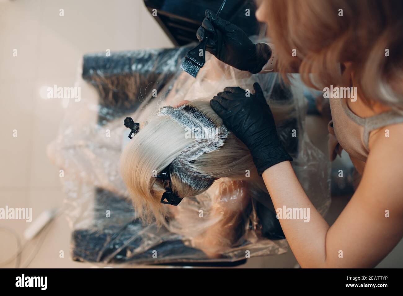 Young woman hairdresser dying hair at beauty salon. Professional hair ...