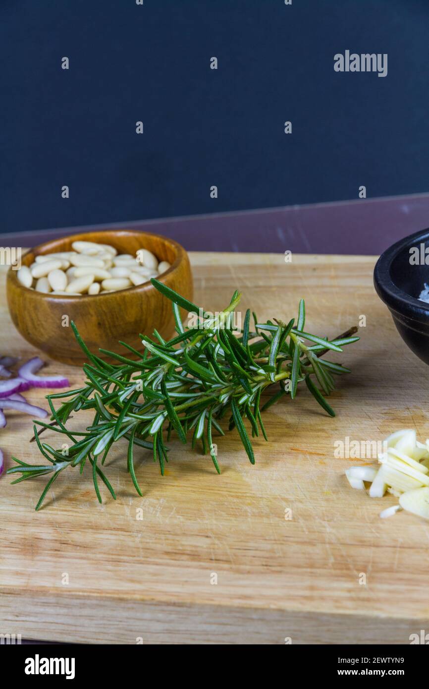 Wood wooden board with onion, rosemary, salt and pine nuts, bowl, pile ...