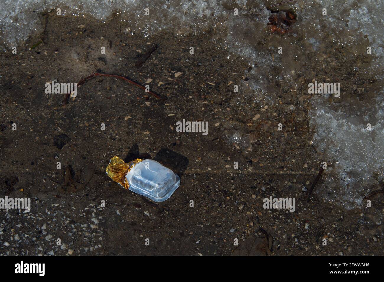 Discarded plastic litter lies near melting snow in a parking lot in ...