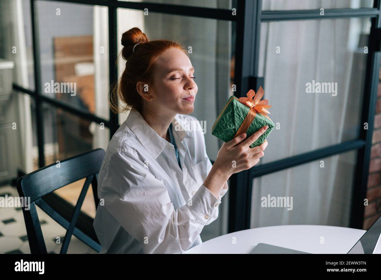 Close-up face of cheerful redhead young woman gently cradling surprise ...