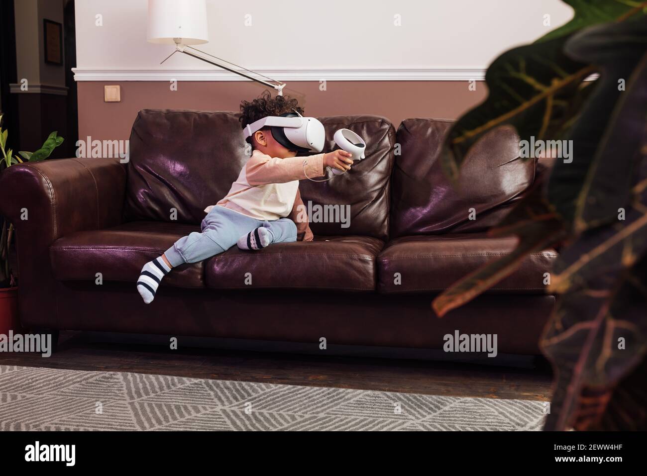 Little boy wearing VR glasses while sitting on sofa. Kid with virtual ...