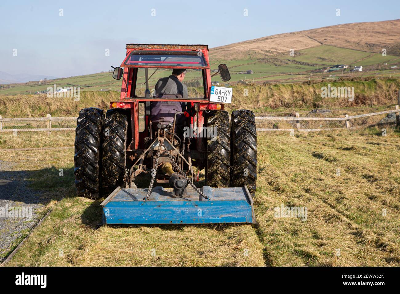 Small grass haulm topper being pulled by a tractor on domestic land ...