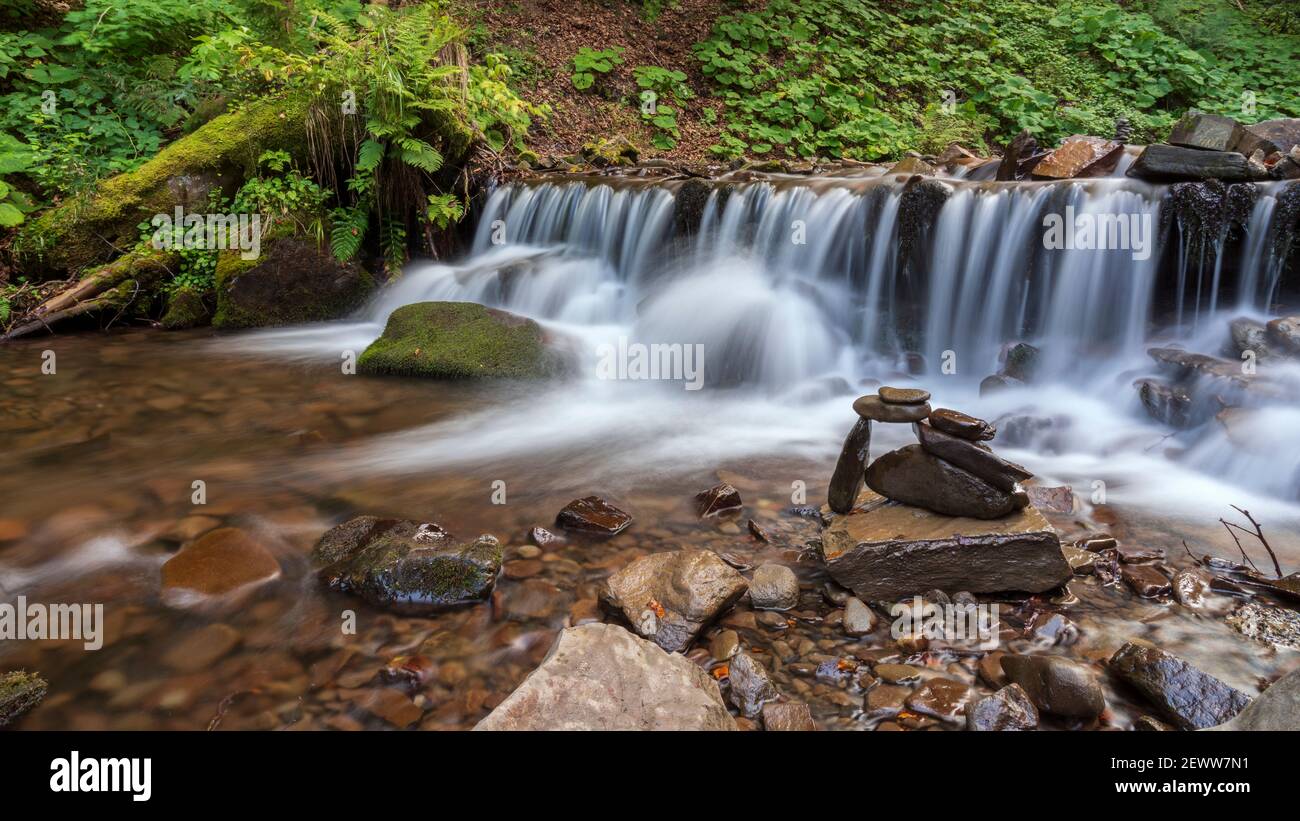 Stacked stones on mountain river side beside the waterfall Stock Photo ...