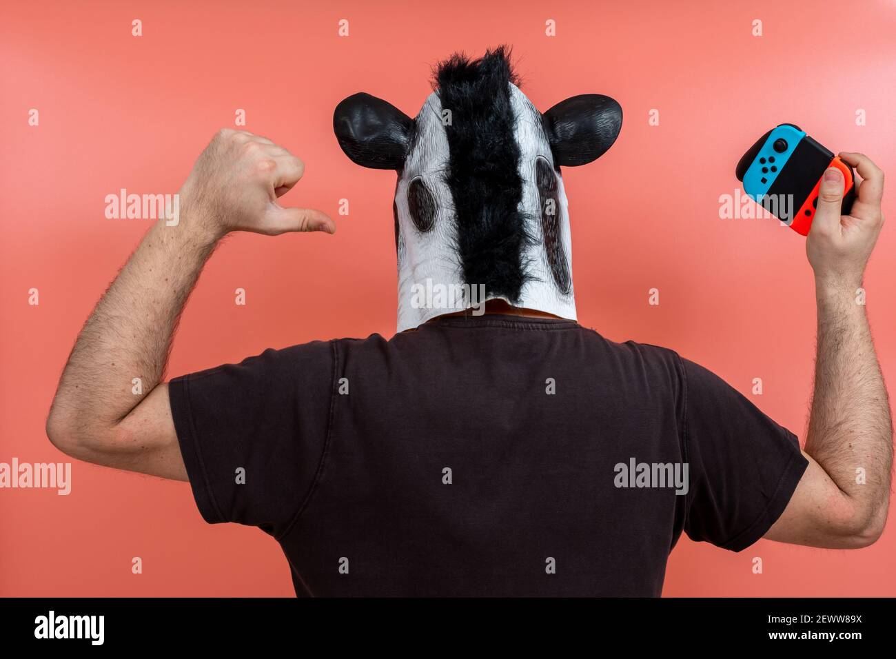 disguised person with a cow mask and a console controller in his hand ...