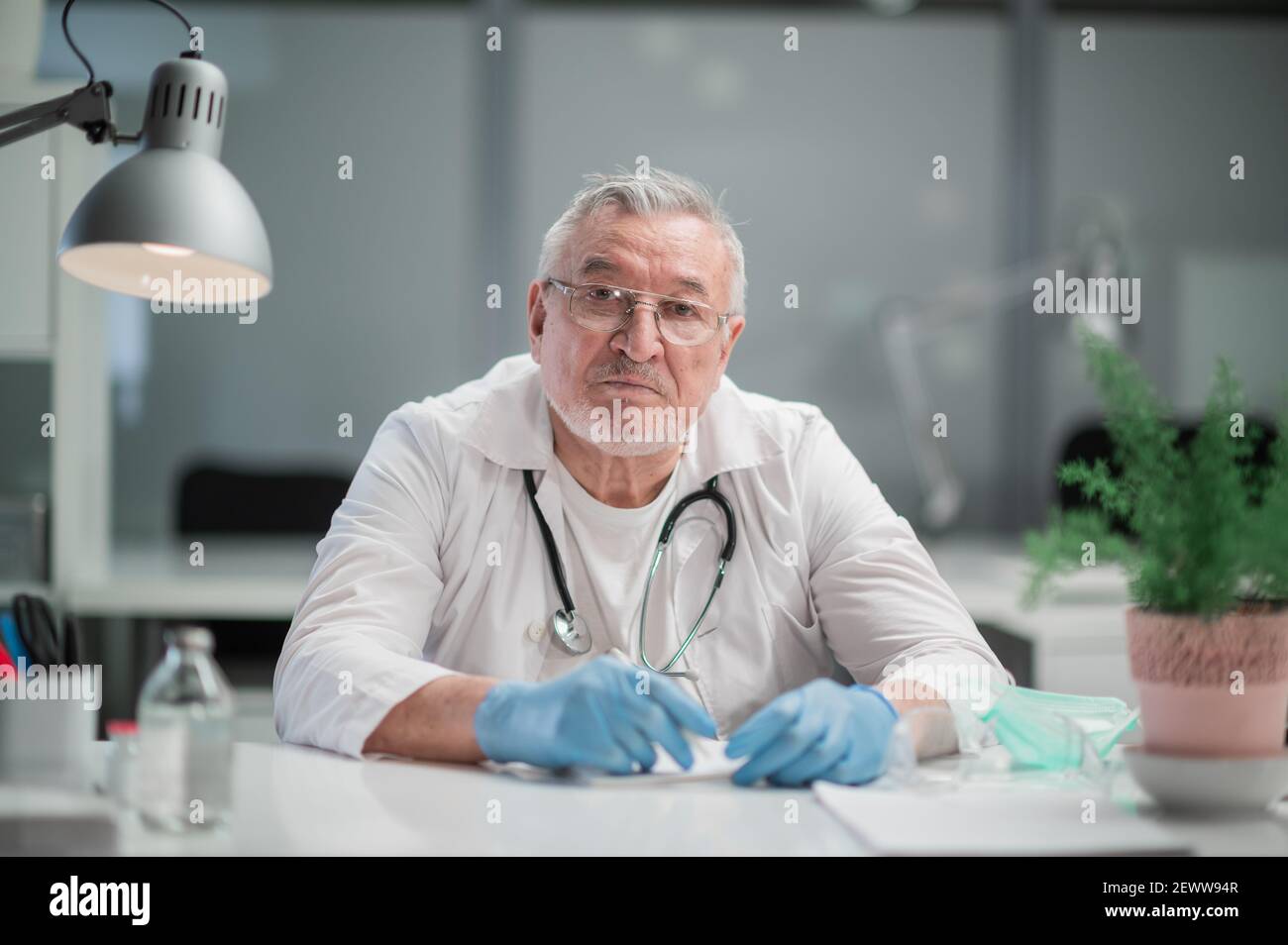 The impressive head doctor of the clinic sits in his office and poses ...