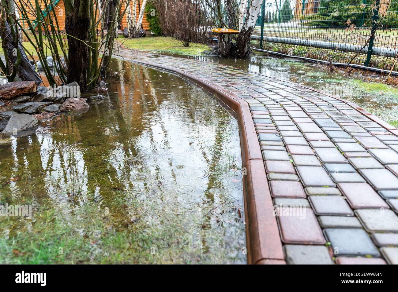 Garden bushes, tree and green grass lawn covered with water due to snow ...