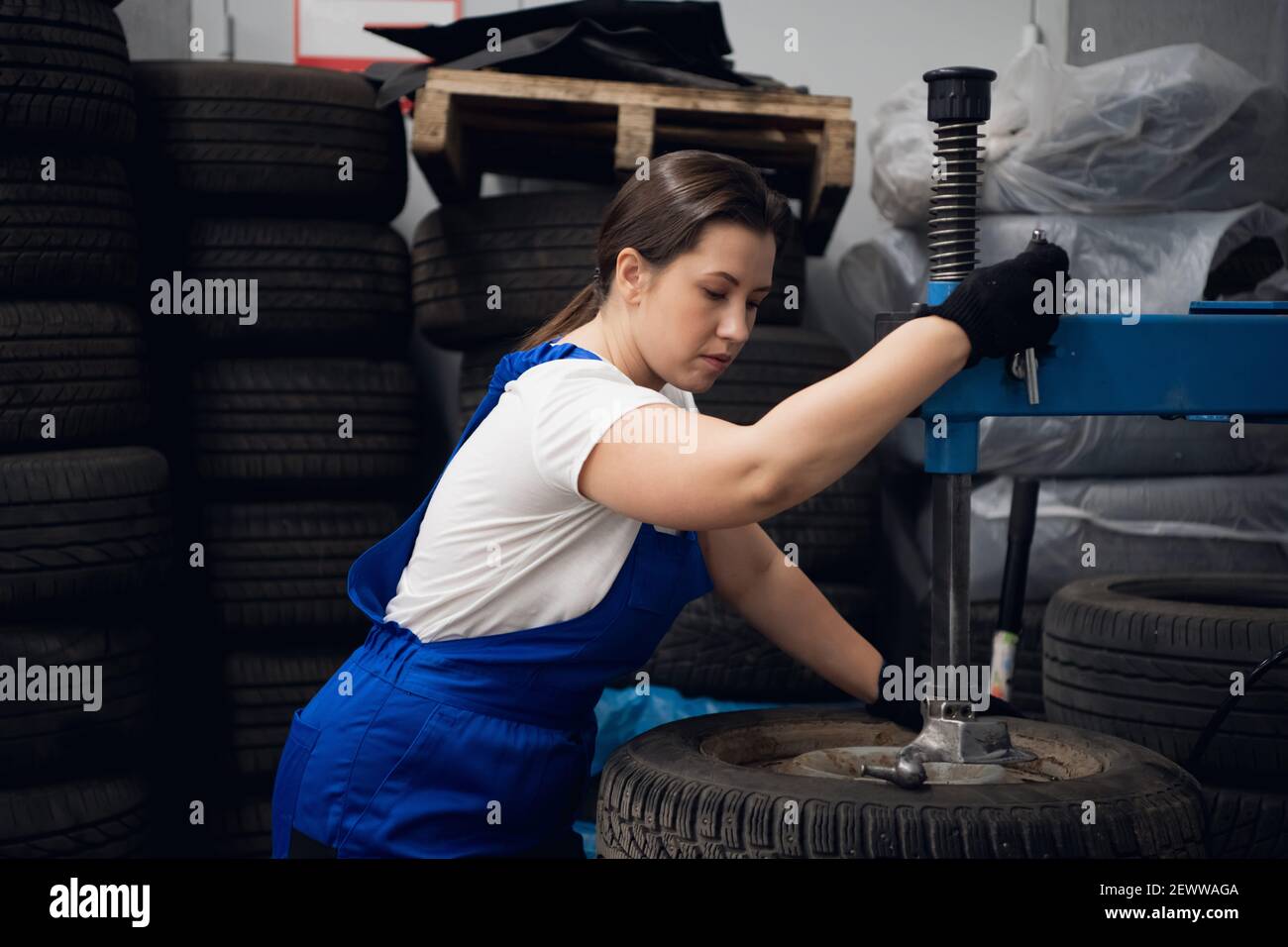 Mechanic in overalls works with a press and wheels Stock Photo - Alamy