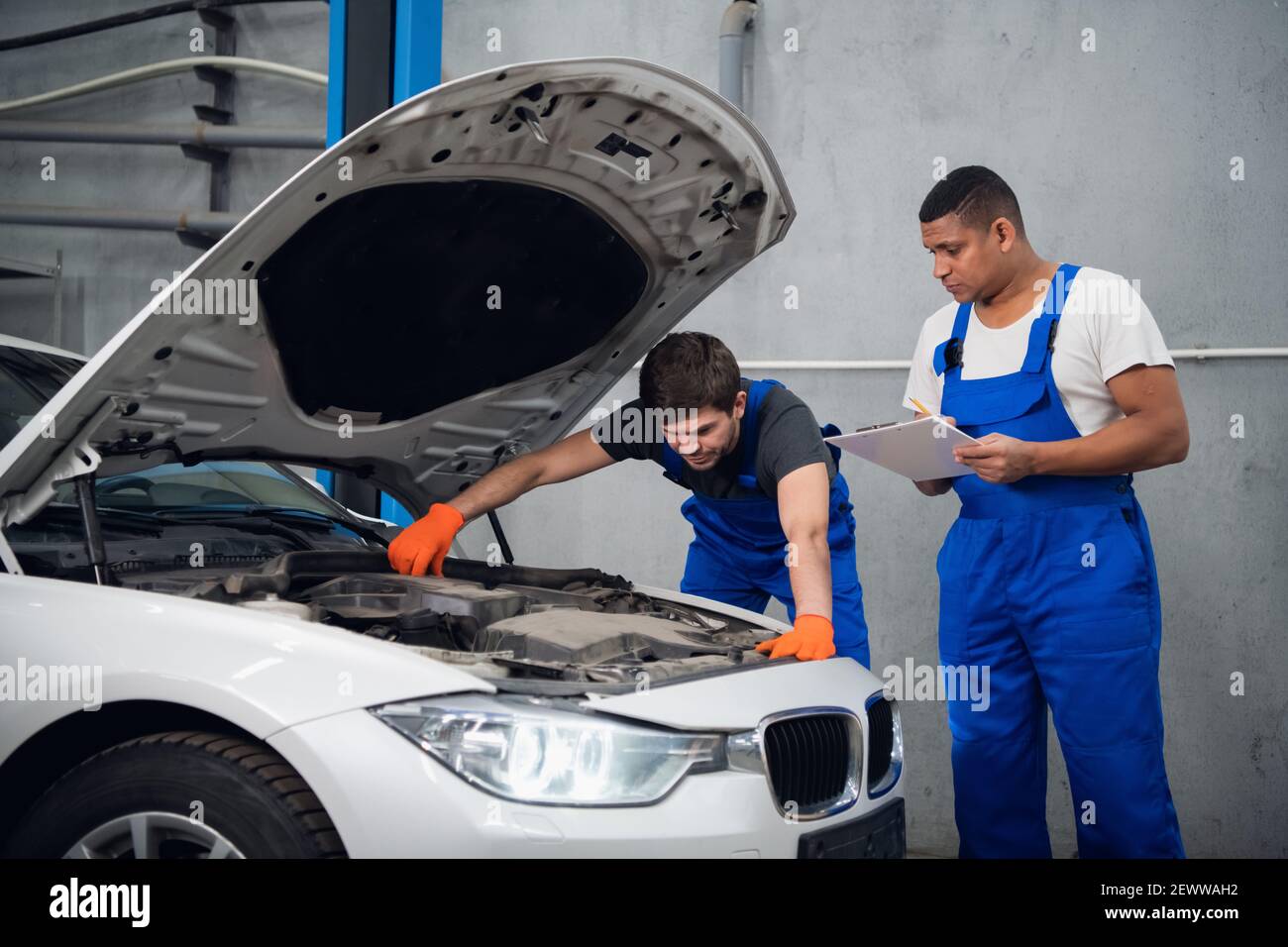 Repairers repair a car engine and write a report Stock Photo - Alamy