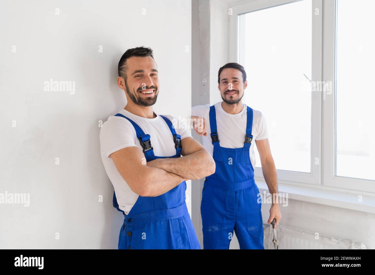 Two builders in overalls look at the camera Stock Photo - Alamy