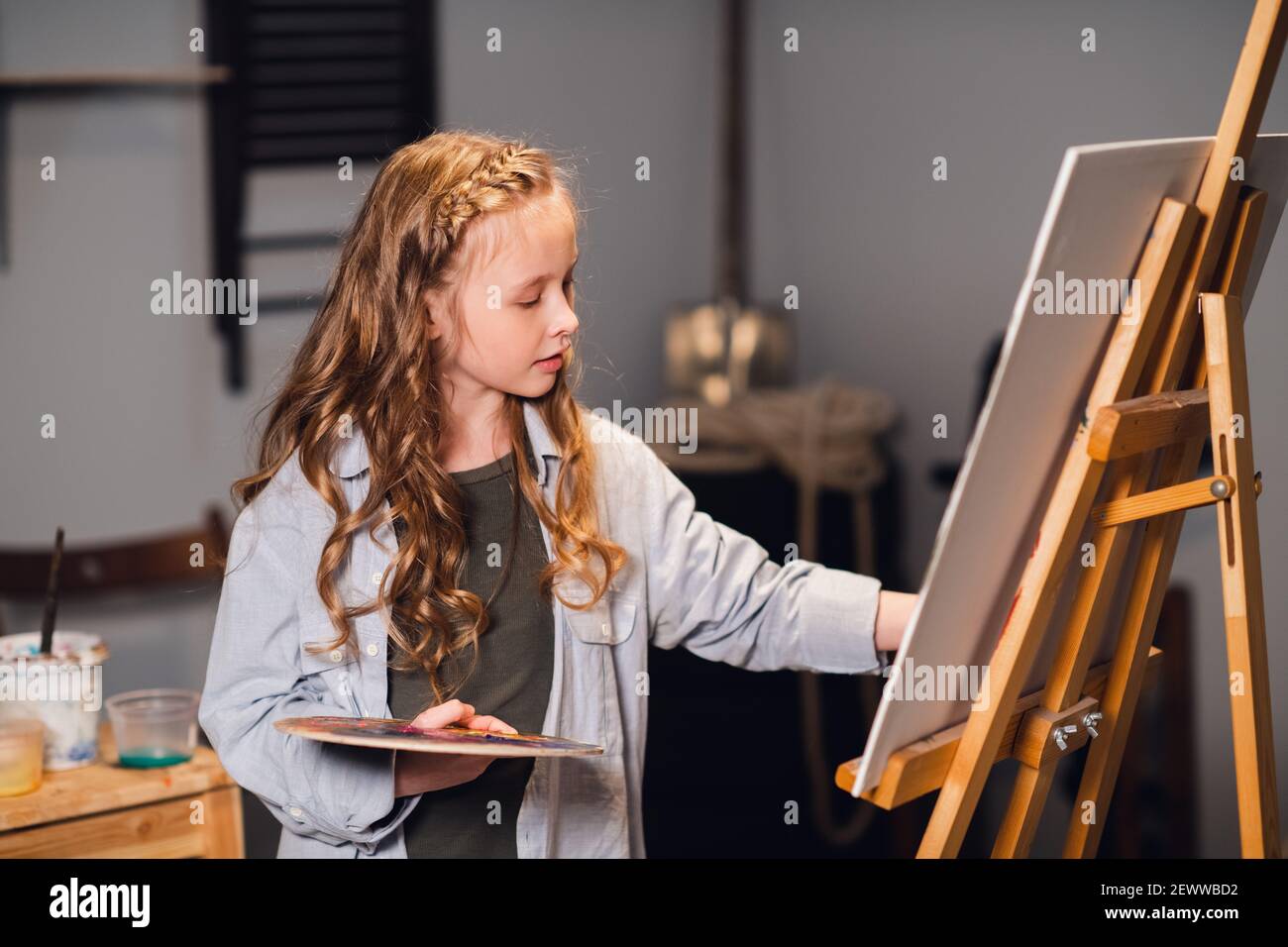 A young cute artist girl is learning to draw in an art workshop. Draws ...