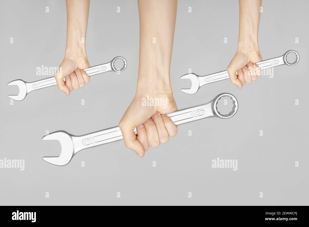 three spanners in the women's hands. hands holds a wrenches on a gray ...