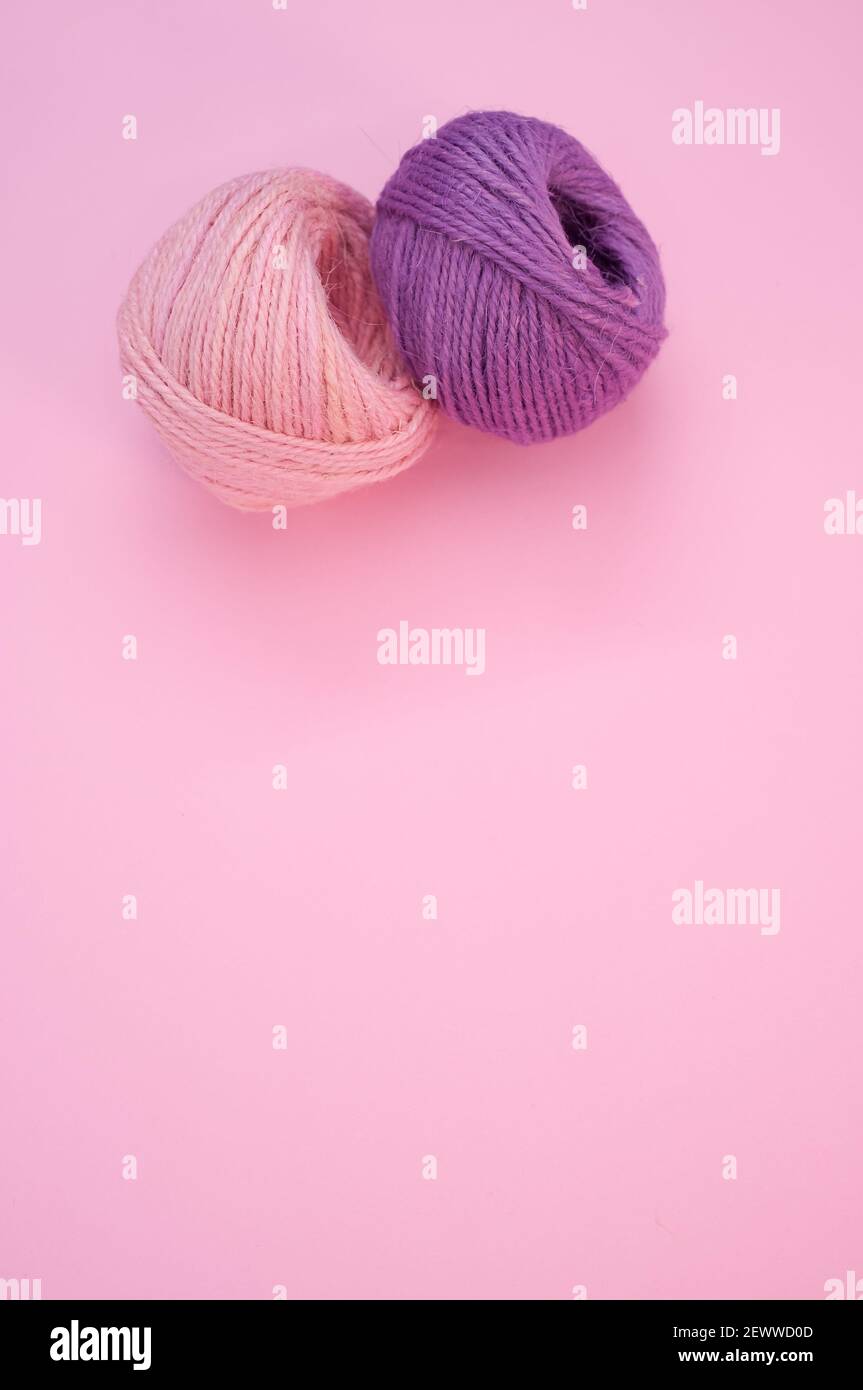 A closeup shot of pink and purple wool yarns on a pink background ...