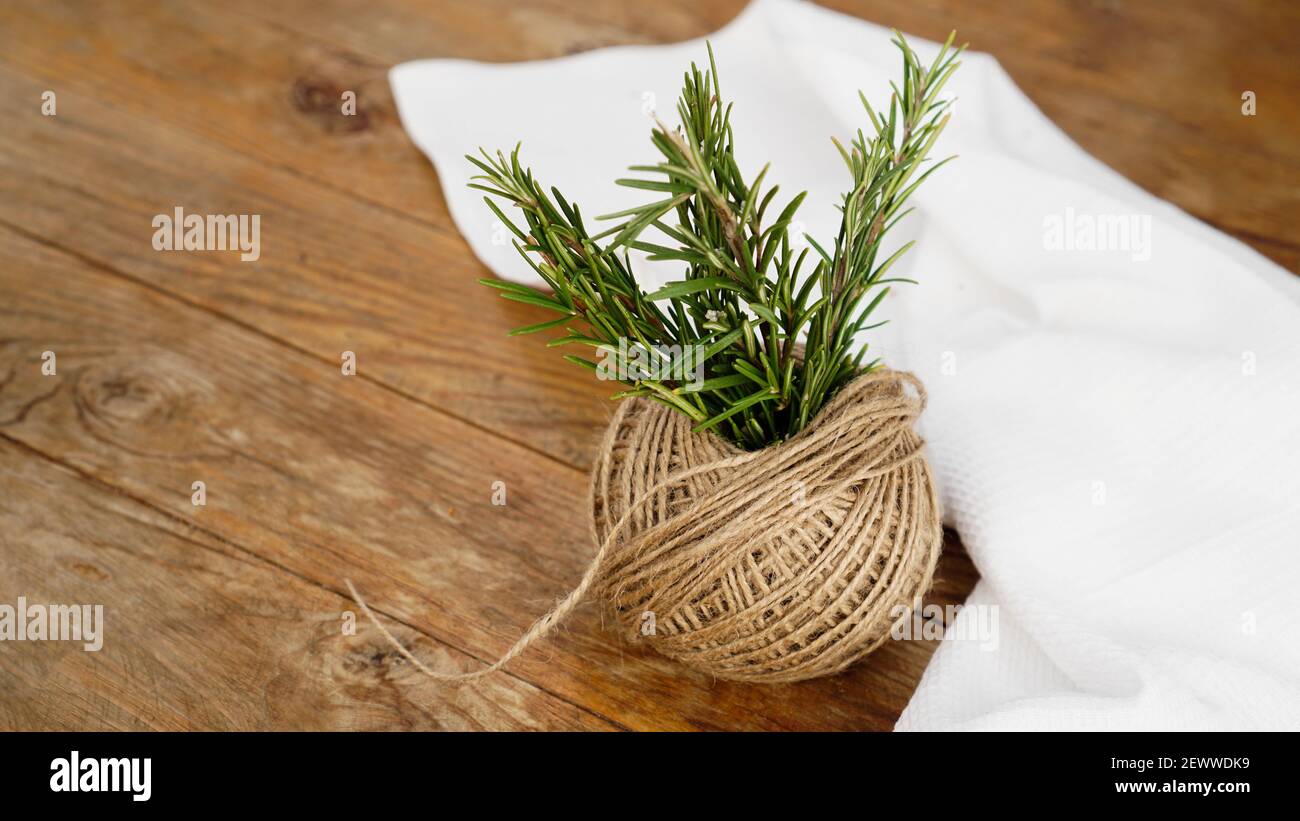 Sprigs of rosemary and skeins of jute rope on a wooden board for ...