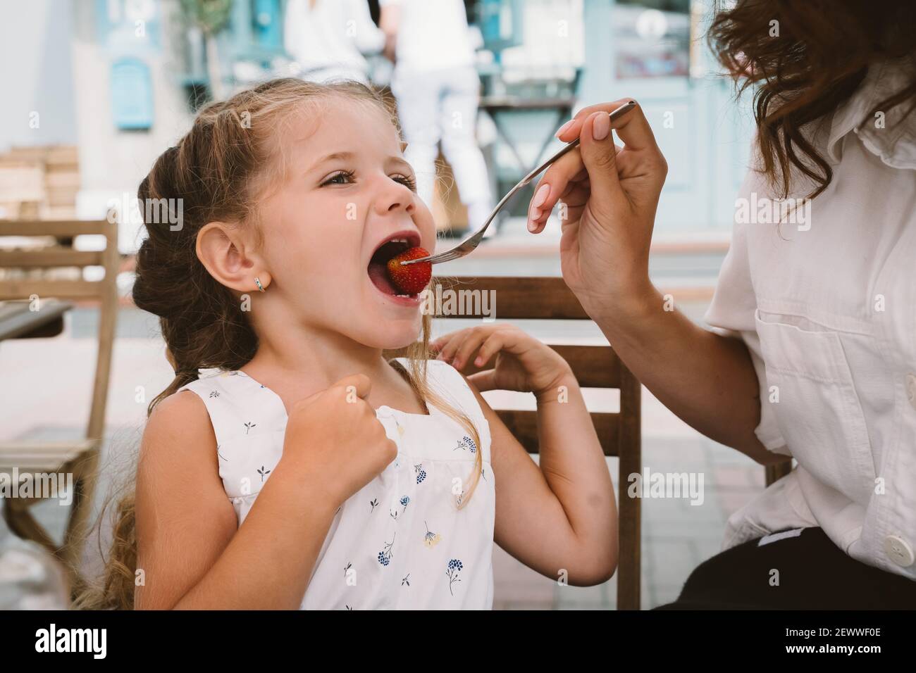 Young mom eating cake with smiling kid on the street Stock Photo - Alamy