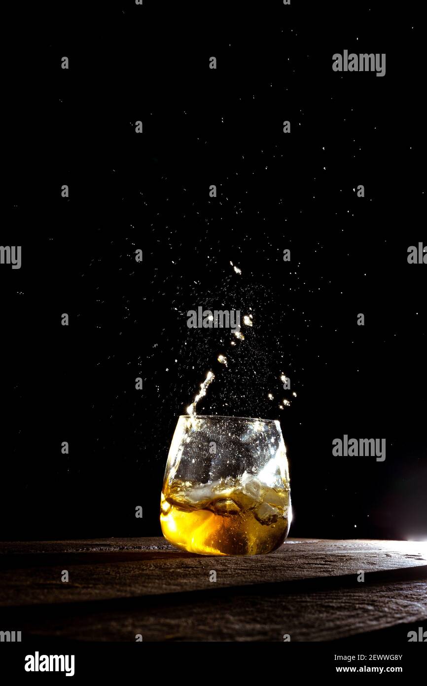 A vertical shot of a refreshing drink with a splash over black ...