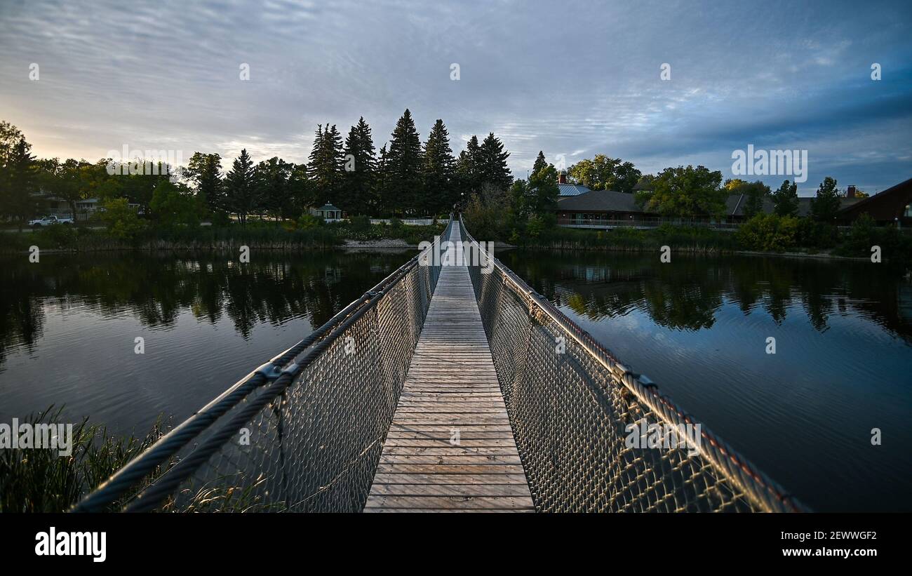 A small wooden bridge with chain-link fenced handrails over a lake in a ...