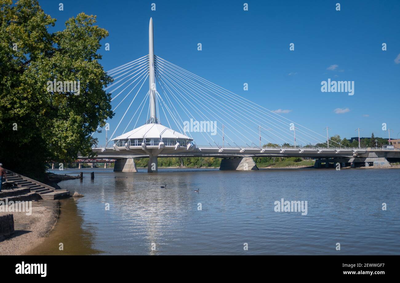 The Esplanade Riel bridge over a lake in a park under a blue sky and ...