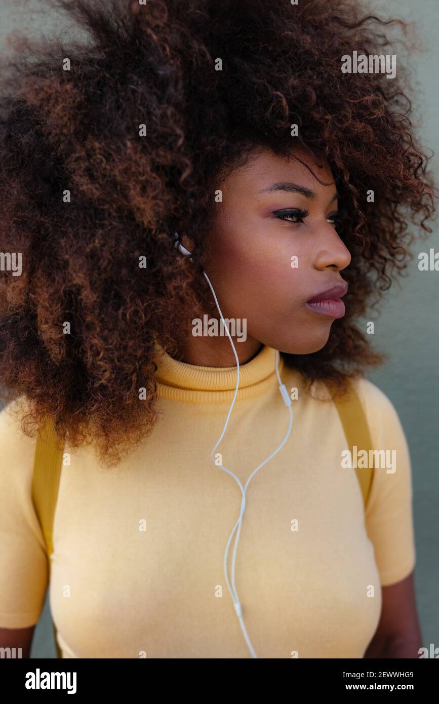 Black Woman with afro hair listening to music with a backpack on her ...