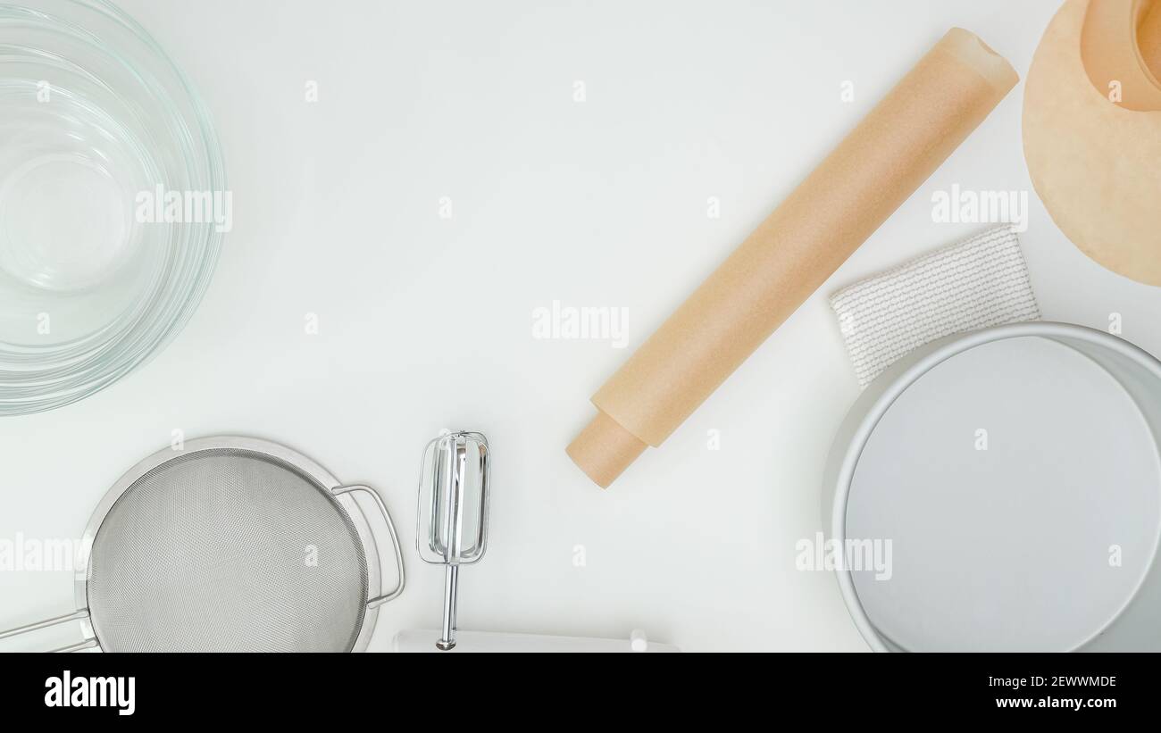Baking pan, parchment paper, mixer, colander close up on white kitchen ...