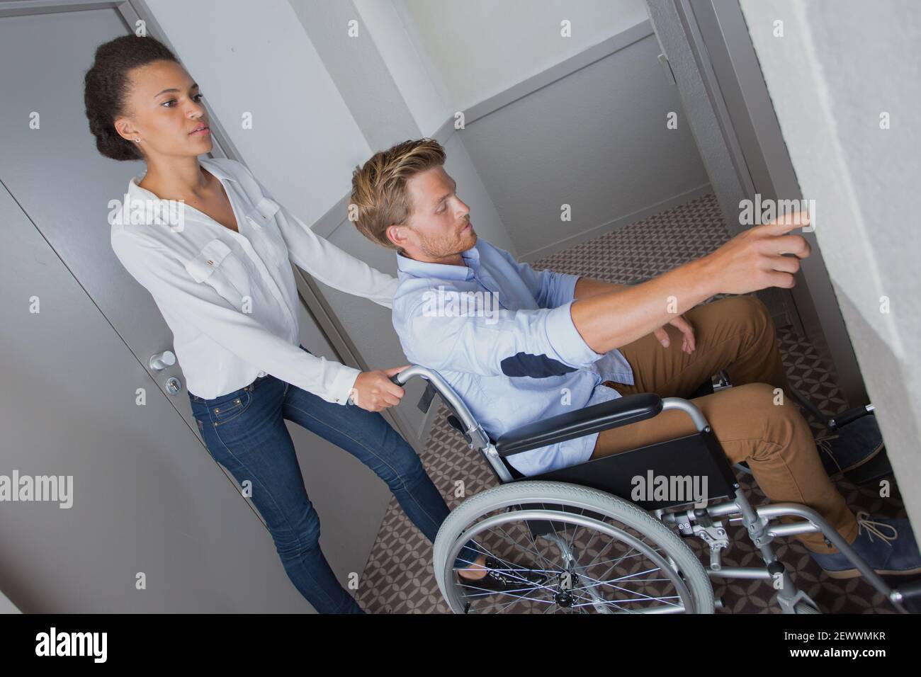 man in wheelchair pressing button for lift Stock Photo - Alamy