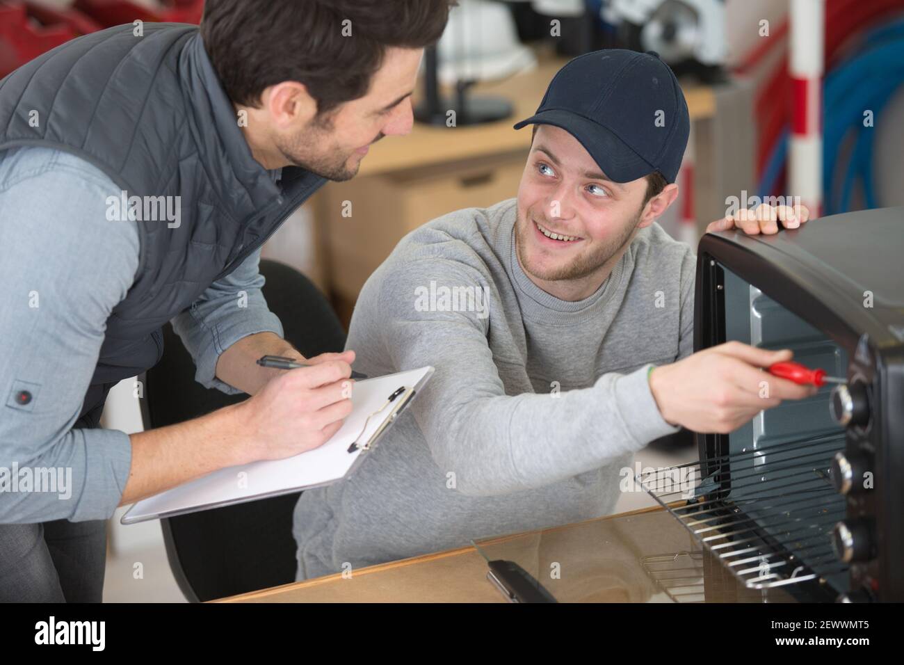 apprentice repairing appliance with his mentor Stock Photo - Alamy