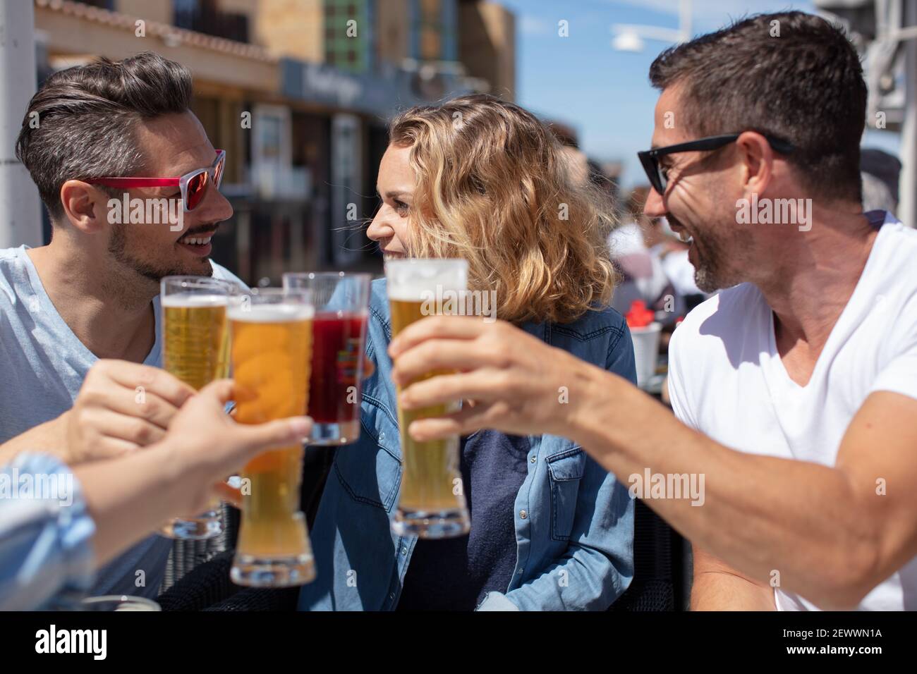 two couples chinking glasses in an outside bar Stock Photo - Alamy