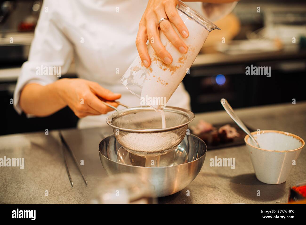 Female chef using strainer while preparing sauce in restaurant Stock ...