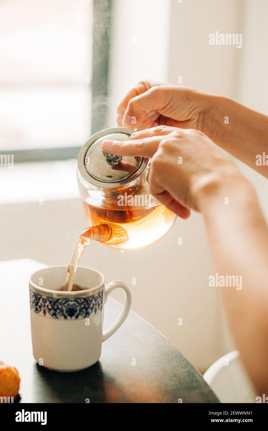 Female hands pouring hot tea in cup Stock Photo - Alamy