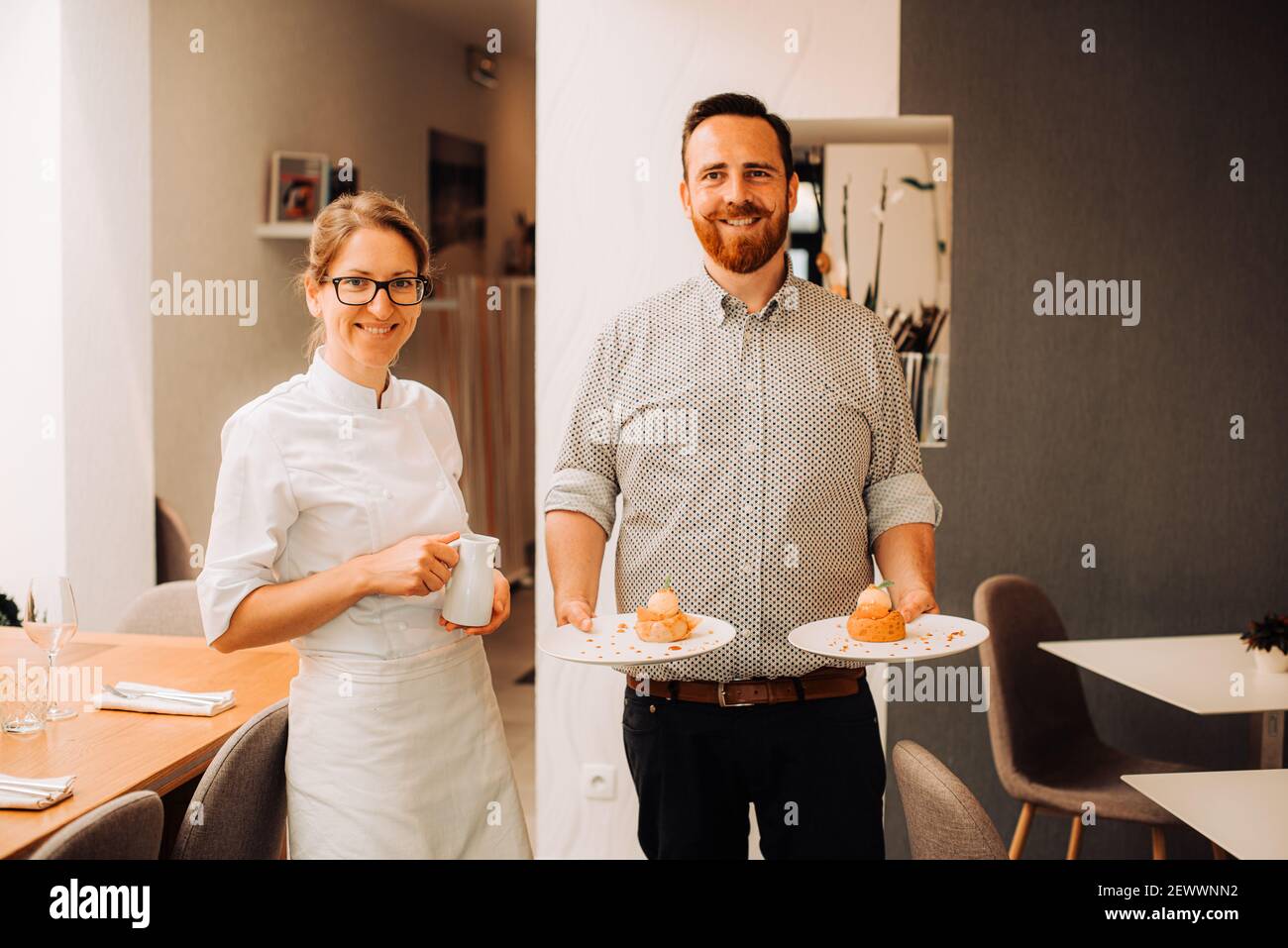 Restaurant team holding plates with dessert with smile while serving ...