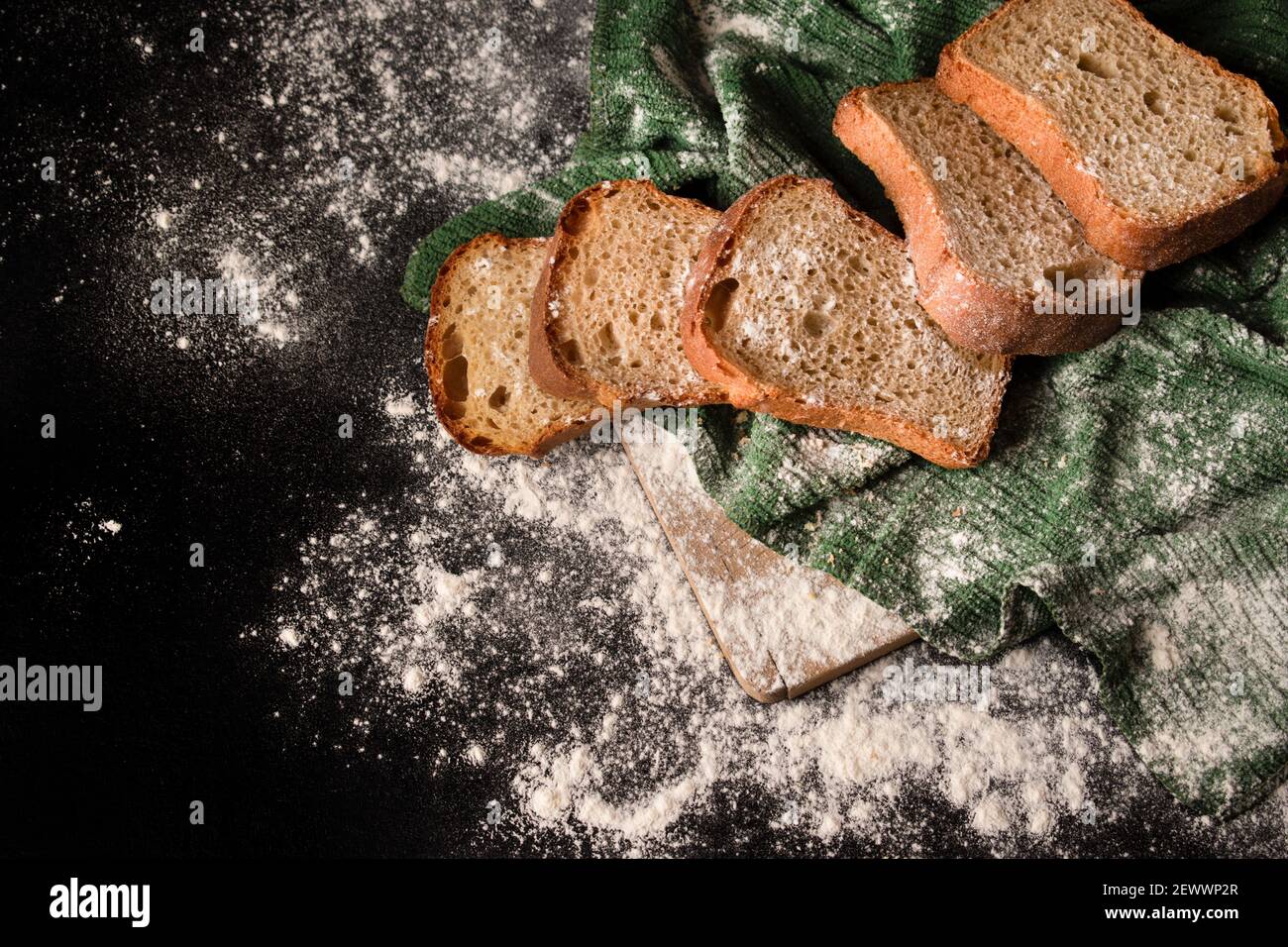 Fresh homemade sliced loaf of bread on fabric textile with spilled ...