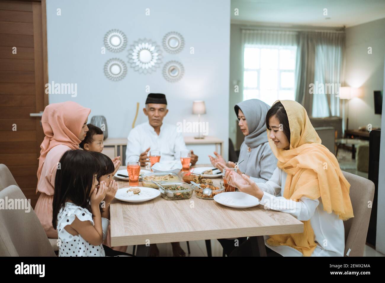 muslim people praying during iftar dinner together with family in the ...