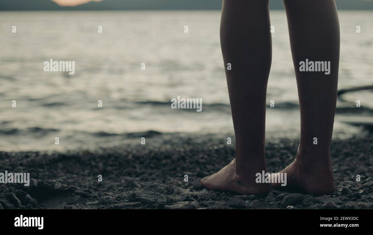 A closeup shotof a person standing on a rocky shore near the sea Stock ...