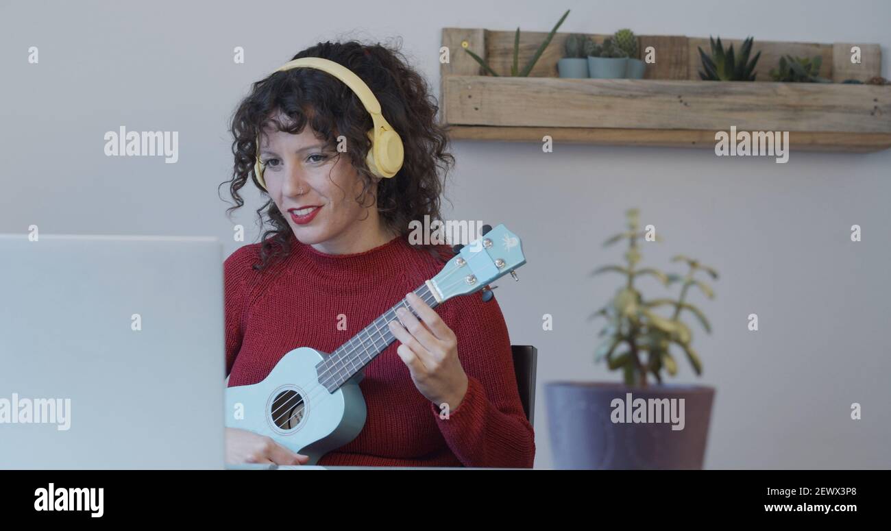 A young female playing the ukulele and watching a tutorial Stock Photo ...