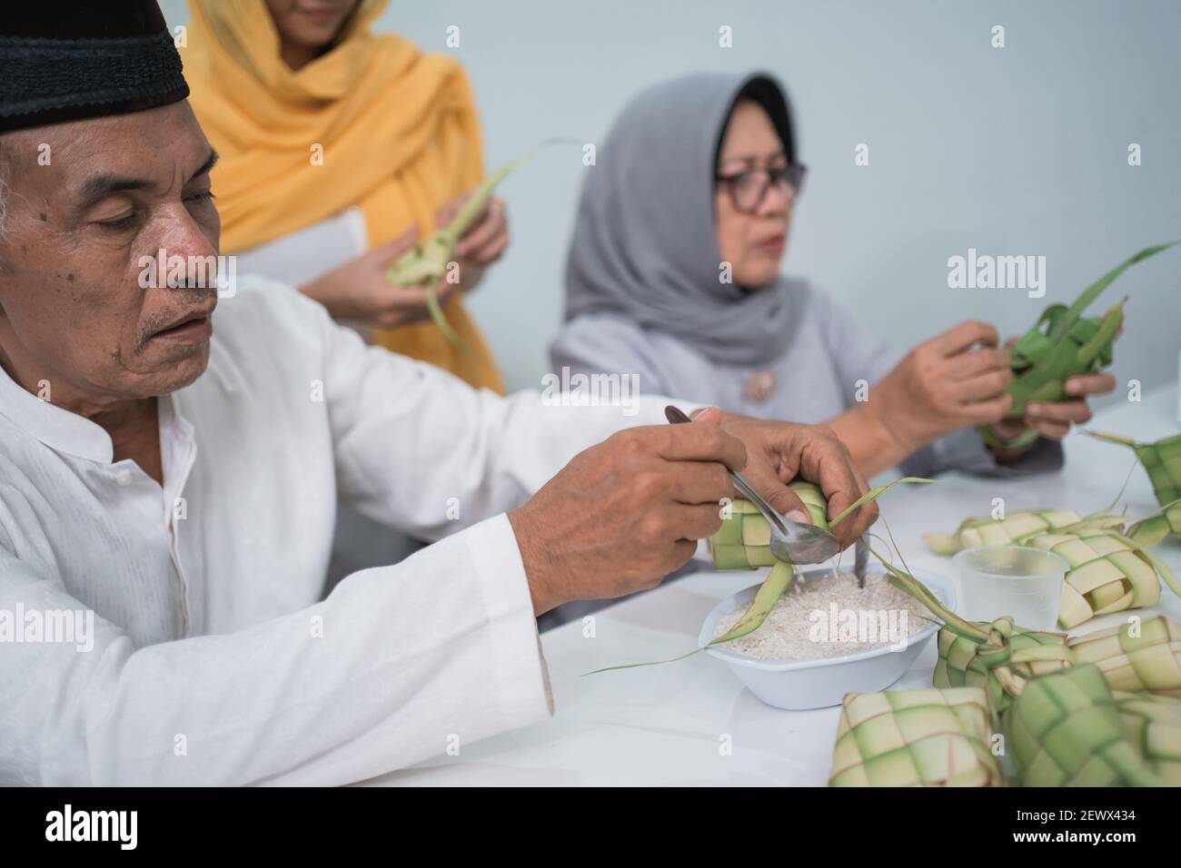 senior muslim couple and daughter making ketupat for eid fitr mubarak ...
