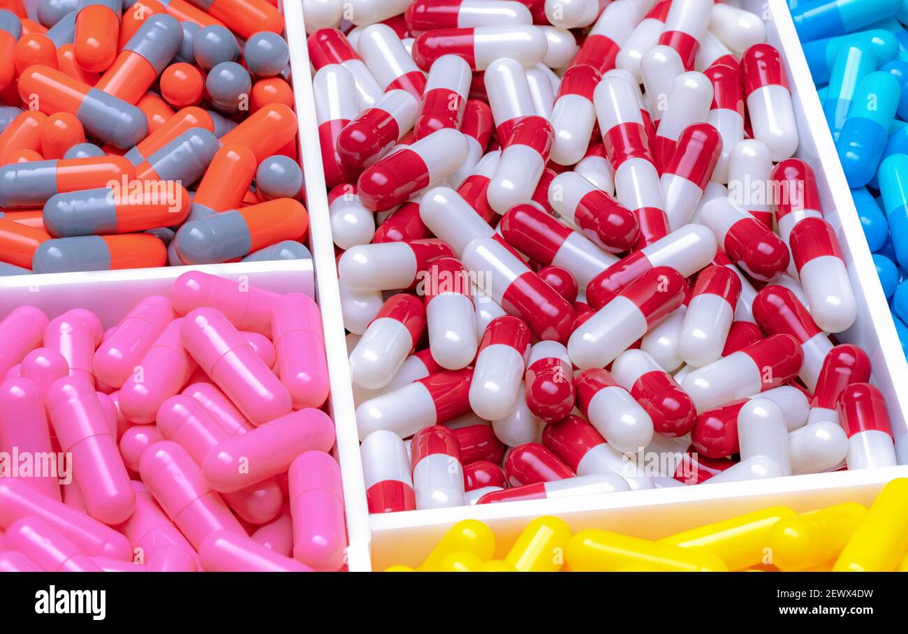 Red-white, orange-gray, pink, blue, and yellow capsules in plastic tray ...