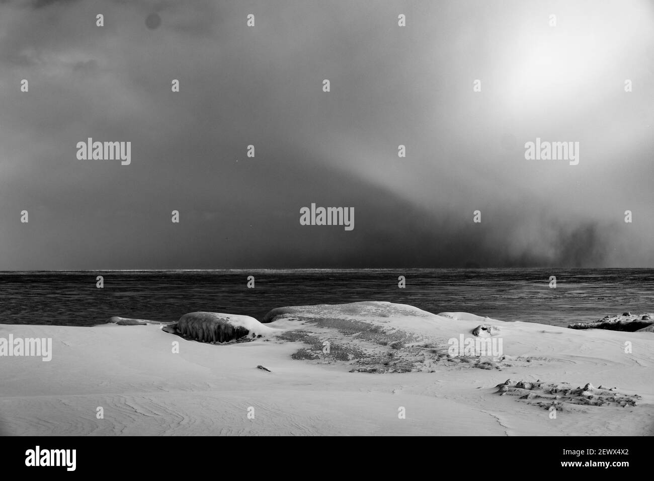 A grayscale shot of a snowy coast and the sea on a cloudy day Stock ...